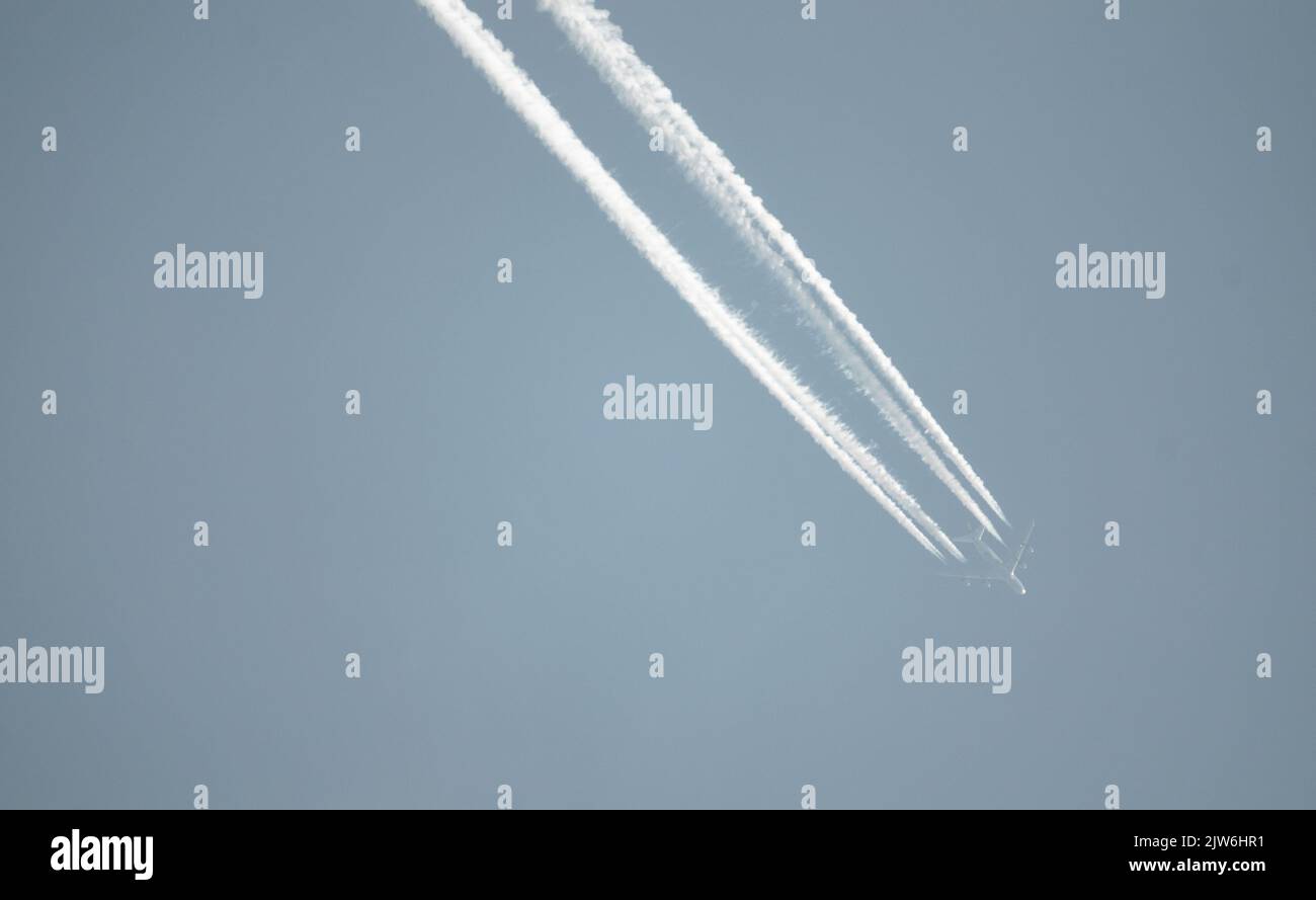 Airliner with a trail high against a blue sky. Steam trace of a jet ...