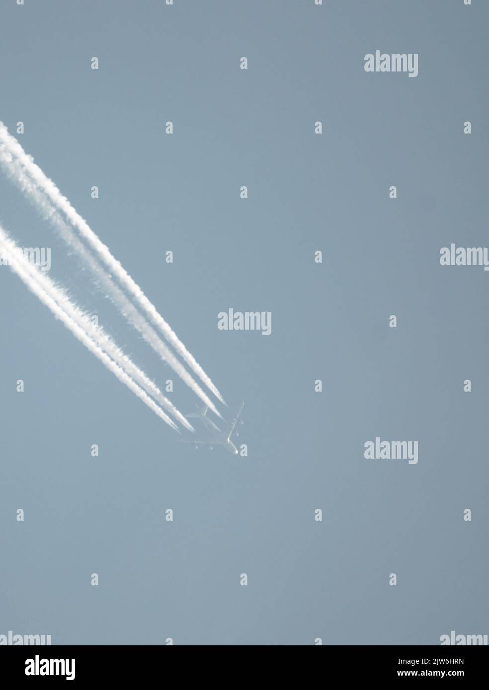 Airliner with a trail high against a blue sky. Steam trace of a jet ...