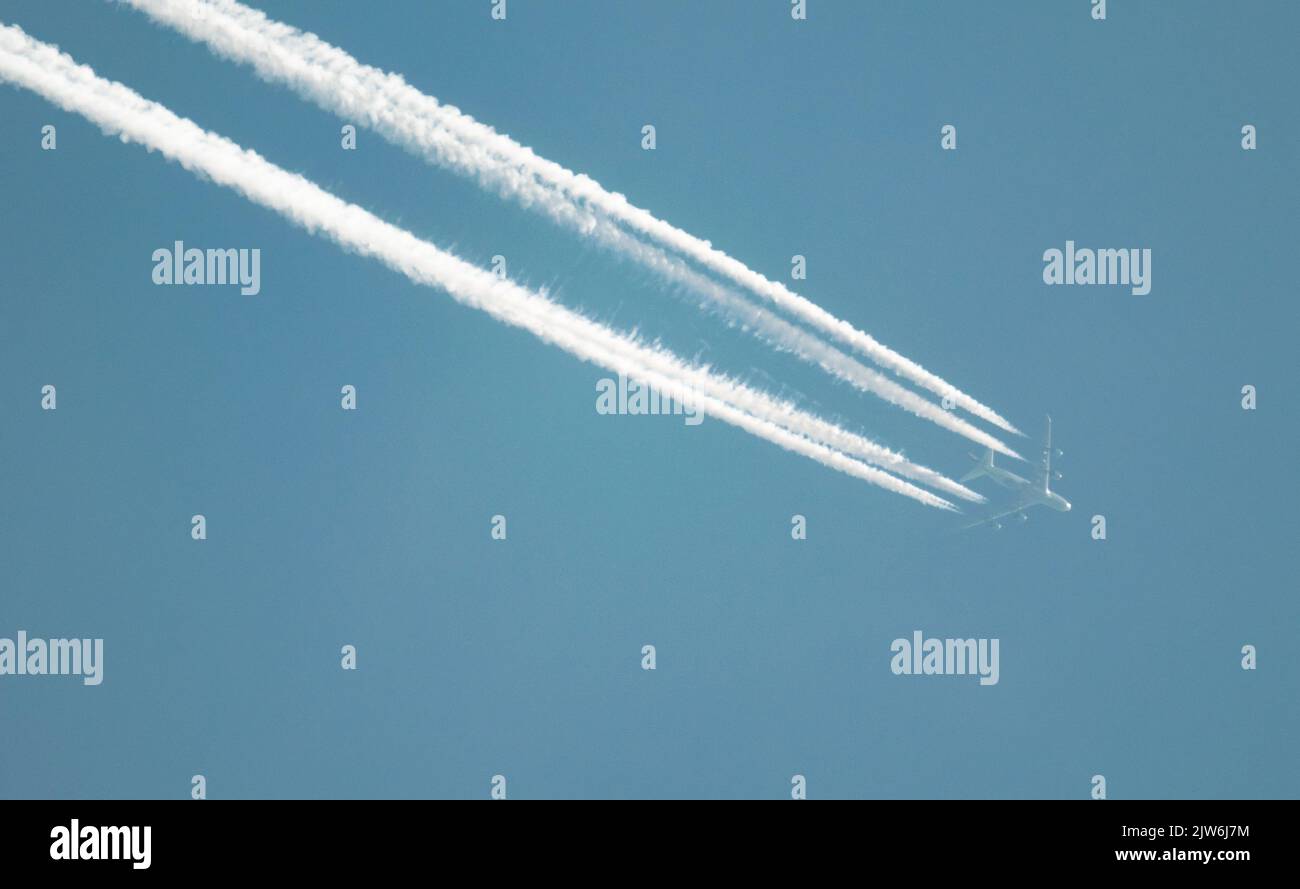 Airliner with a trail high against a blue sky. Steam trace of a jet ...