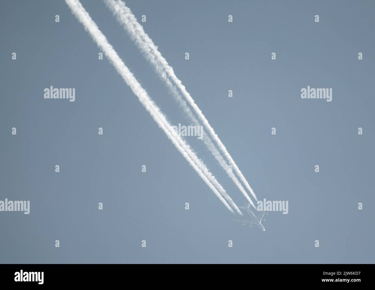 Airliner with a trail high against a blue sky. Steam trace of a jet ...