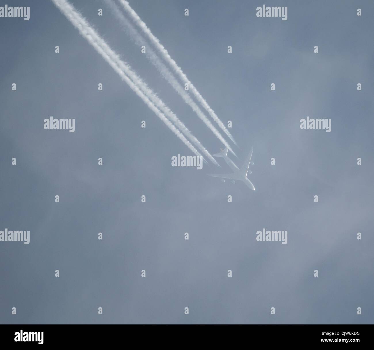 Airliner with a trail high against a blue sky. Steam trace of a jet ...
