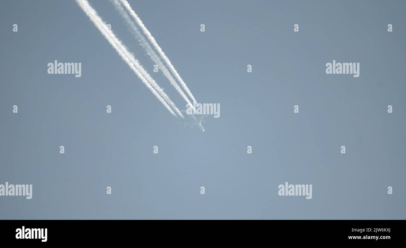 Airliner with a trail high against a blue sky. Steam trace of a jet ...