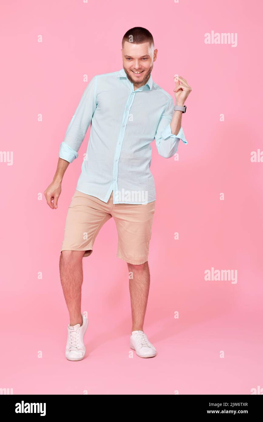 cheerful young happy man dance on pink background. vacation summer ...
