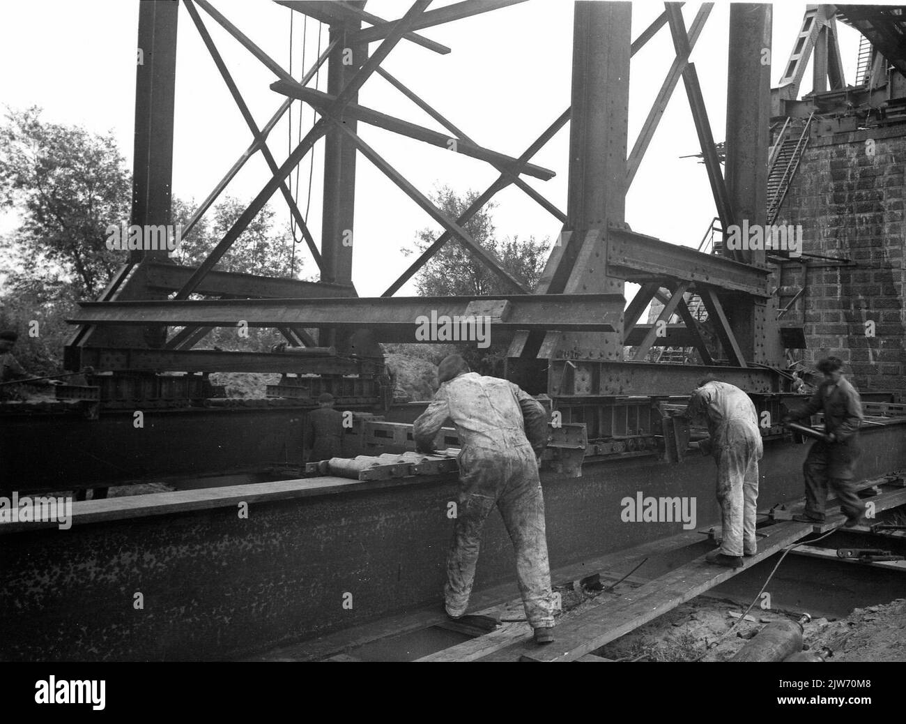 Image of construction workers while rolling in a bridge part for the ...