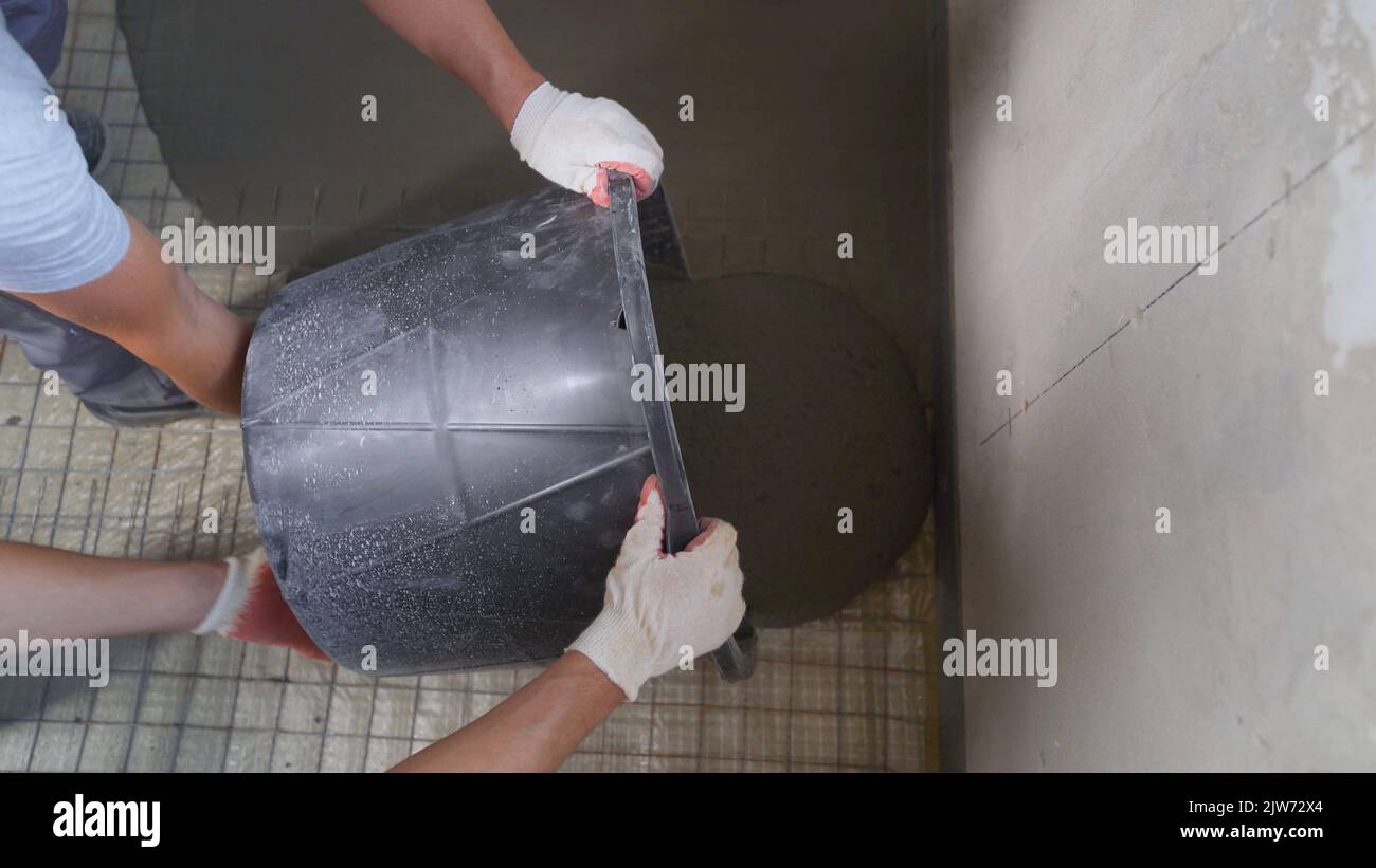 Workers pour the floor in the room with a mortar mixture. Self-leveling ...
