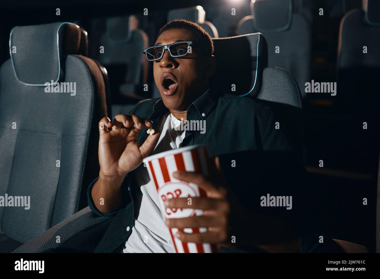 A man is watching a movie in the cinema. The emotion of fright, fear ...