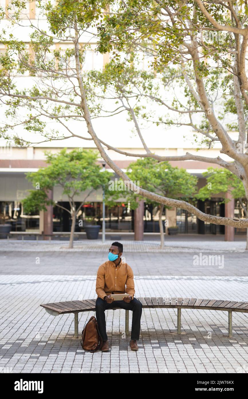 African american man sitting on a bench wearing face mask Stock Photo ...
