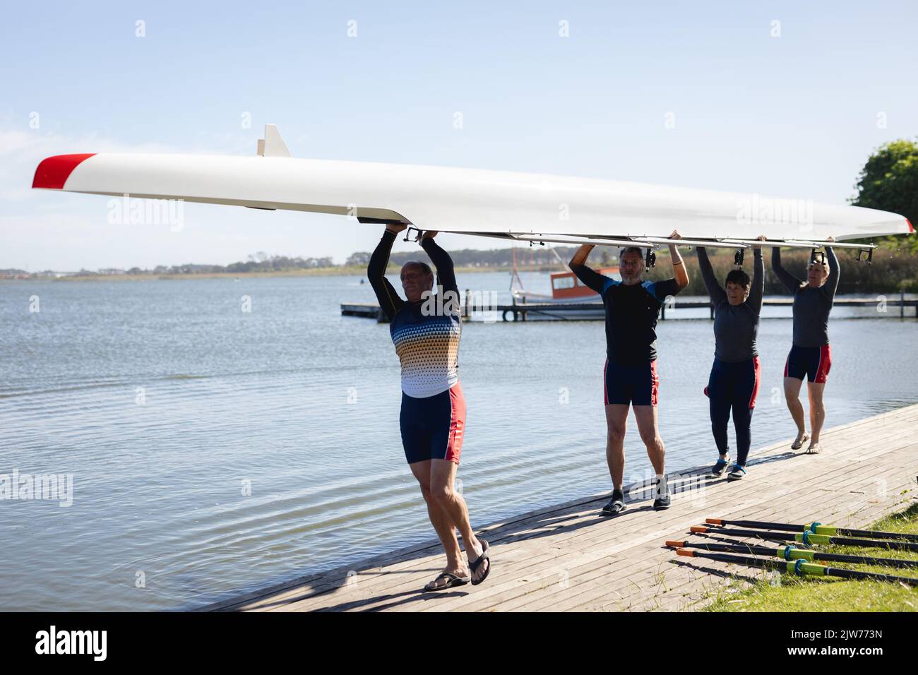 Senior caucasian rowing team carrying boat together to the lake Stock ...