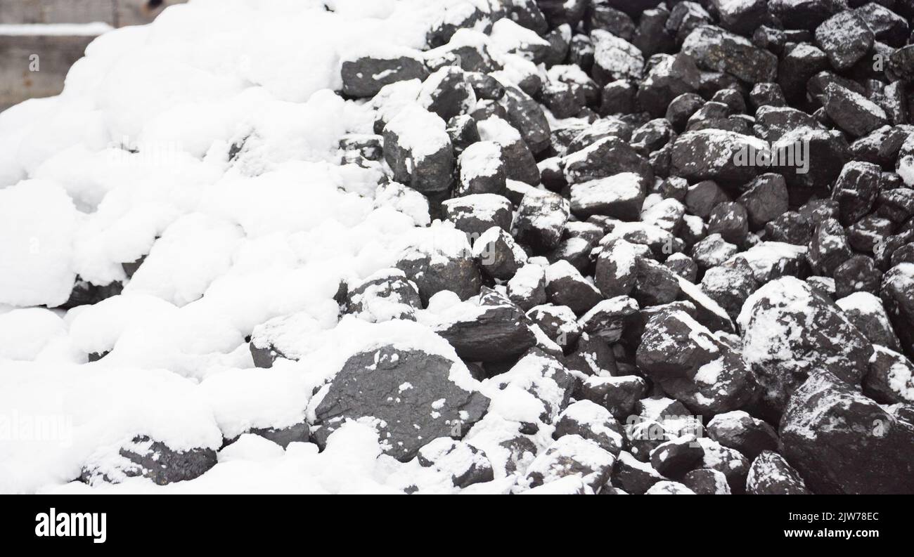Coal covered with snow in the fuel store. Sale of coal in winter. Coal ...