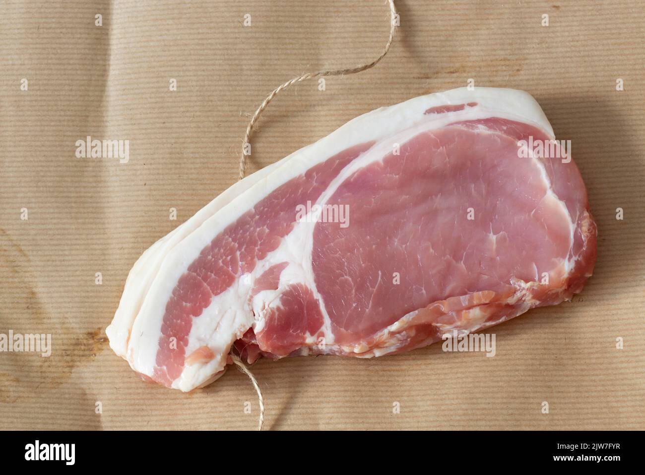 Raw smoked thick cut bacon slices wrapped in brown paper with string ...