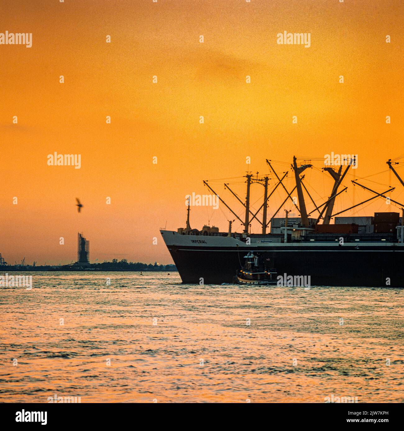 New York, 1980s, cargo boat, Liberty island in the distance, sunset ...