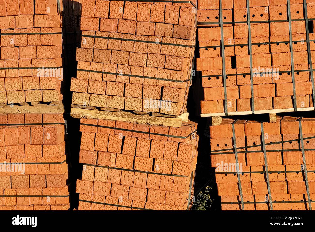 Brown bricks stacked on pallets along construction site fence Stock ...