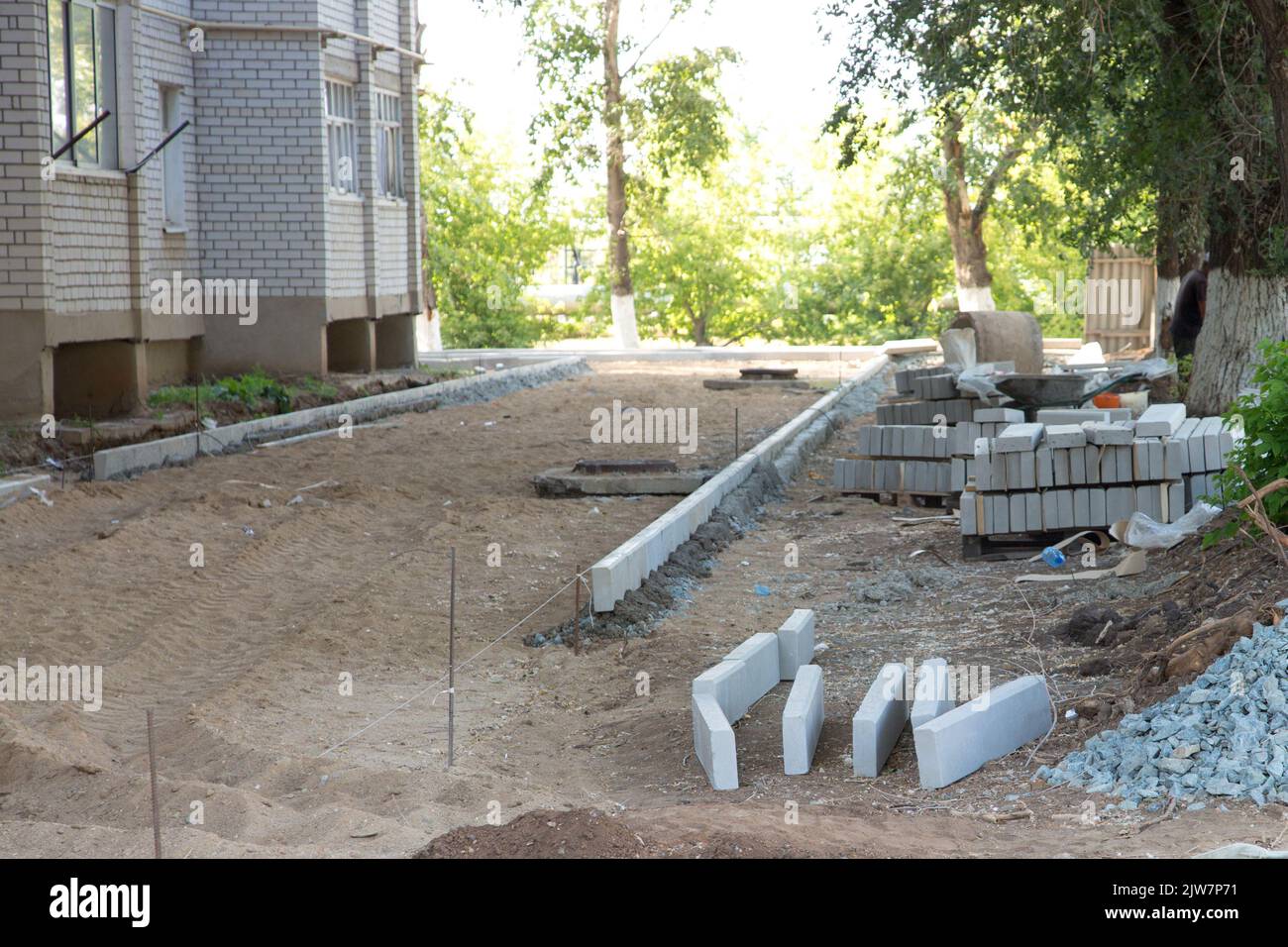 Laying pedestrian path along the house. Even layer of sand prepared ...