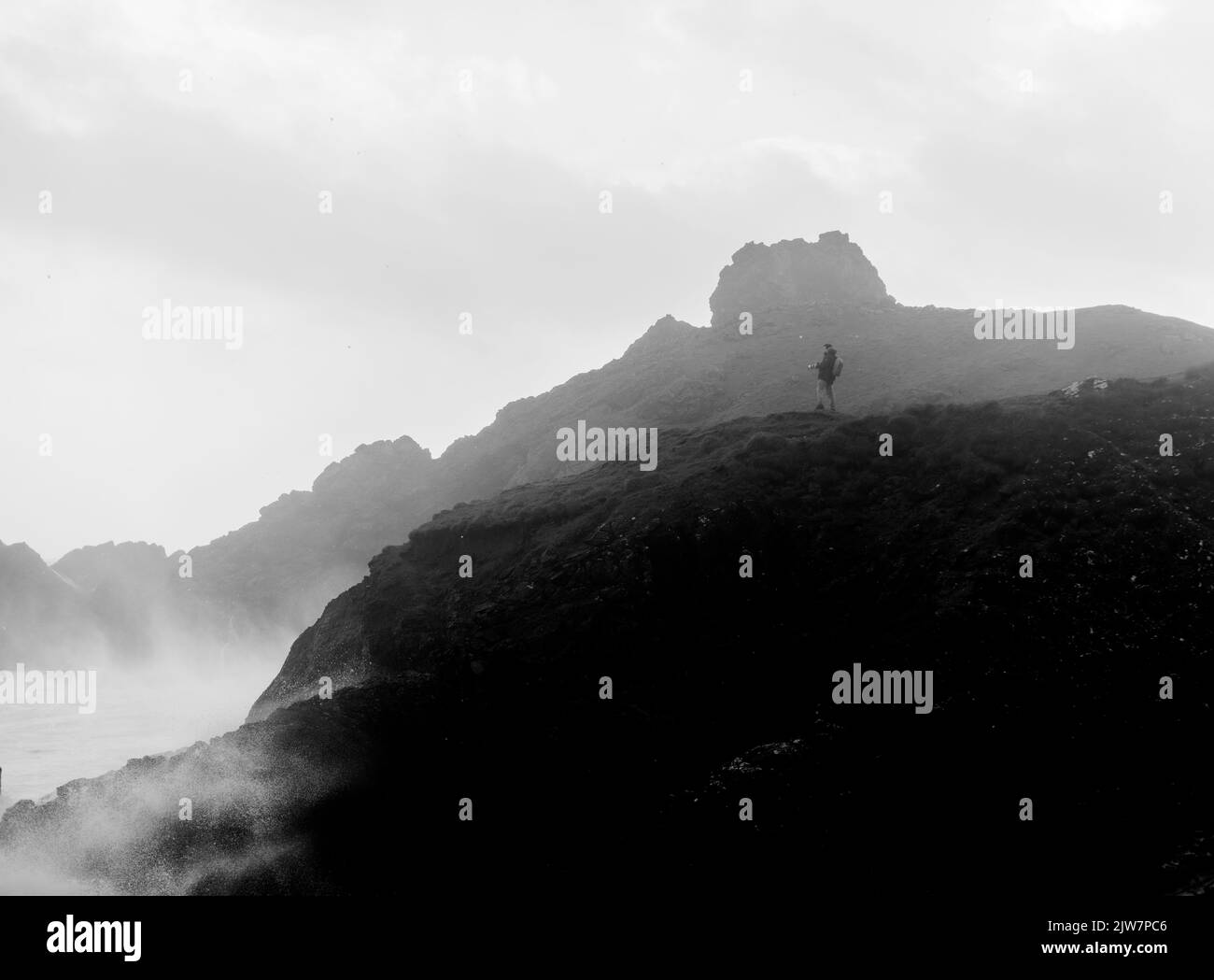 Man standing on the edge of Kynance cove cliffs during a massive storm ...
