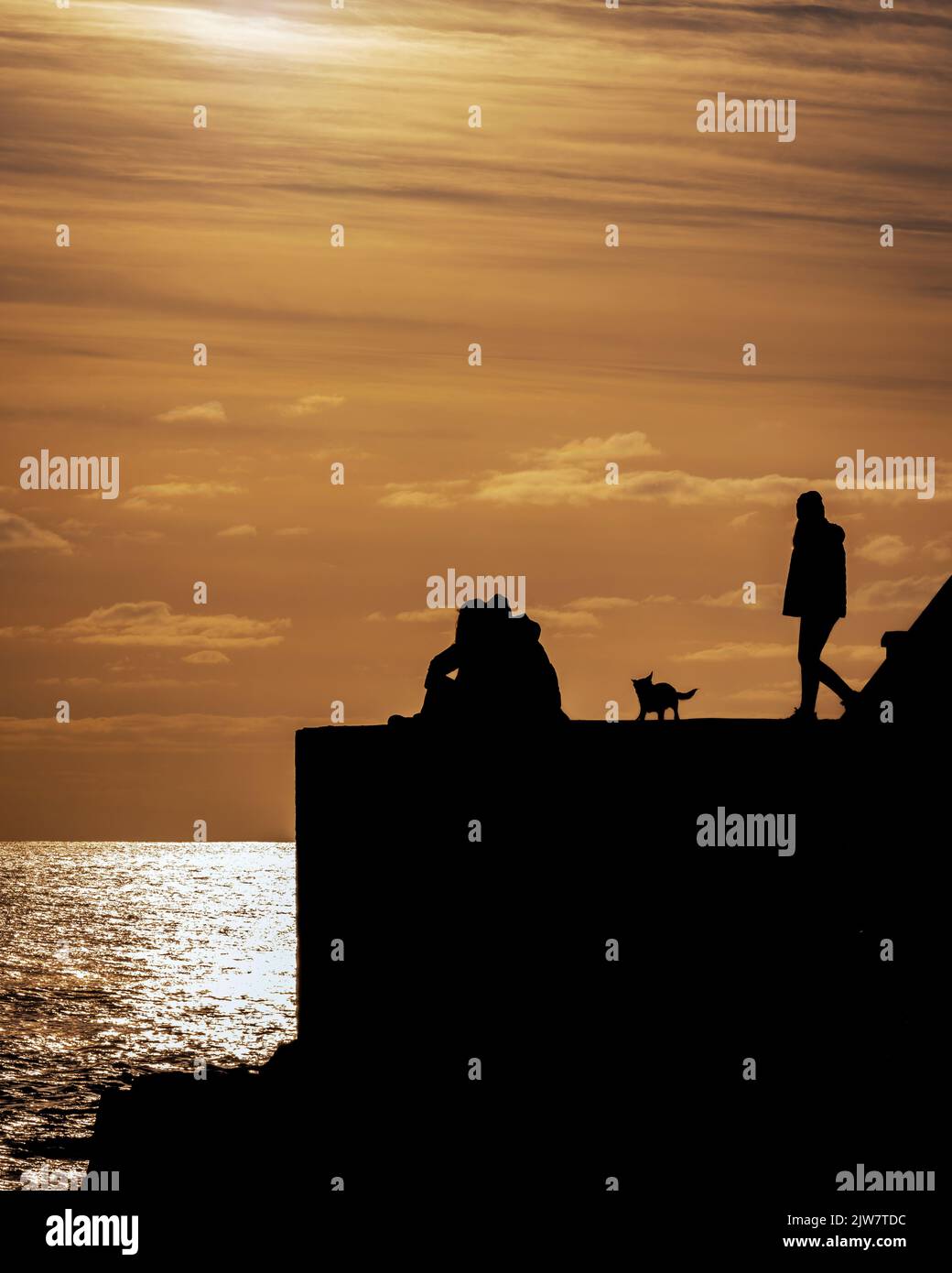 Family's in silhouette enjoying the sun sat at Porthleven Lifeboat ...