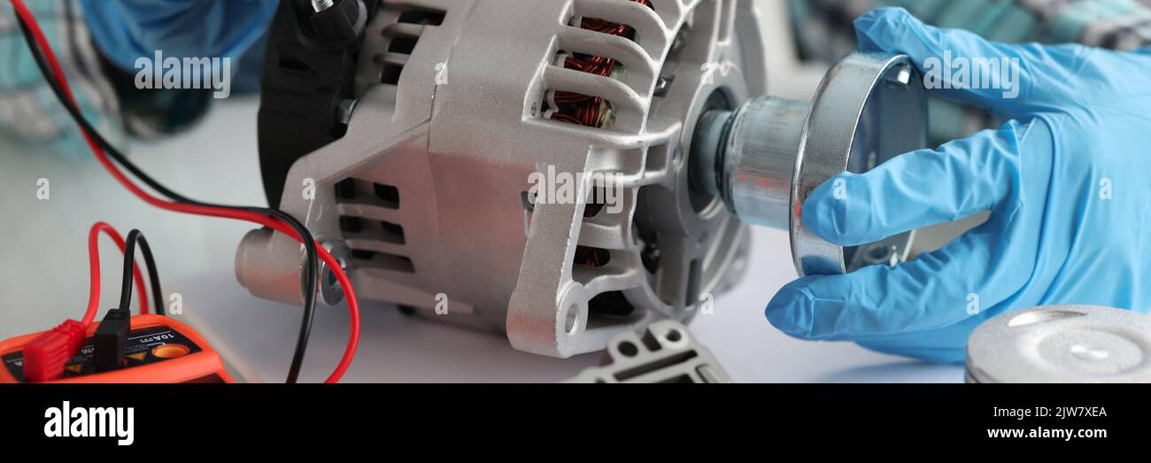 Master repairman diagnosing breakdown of car generator using tester ...