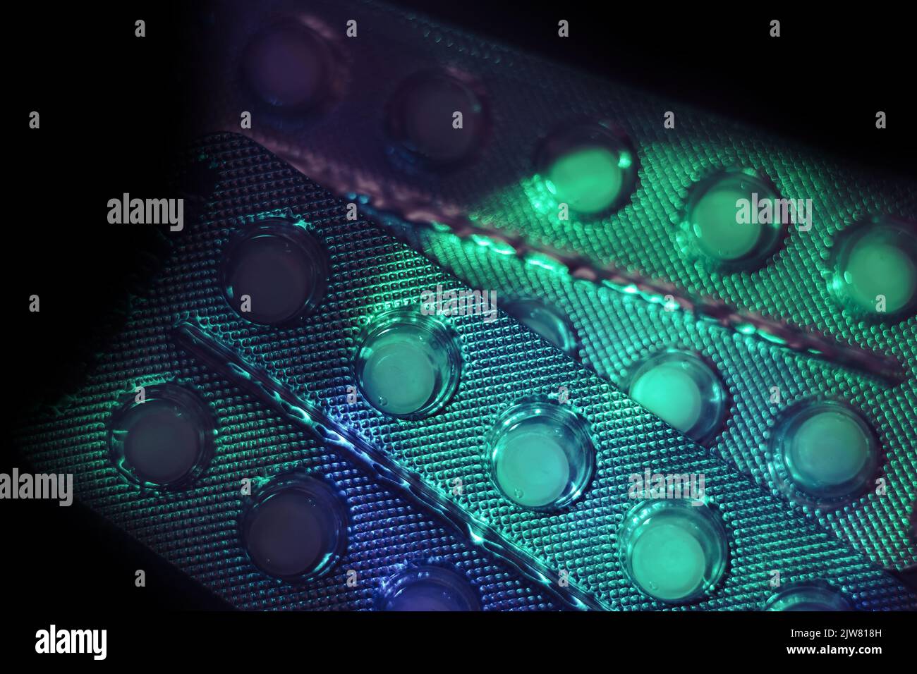 Pills or drugs in a package under neon light on a dark background ...