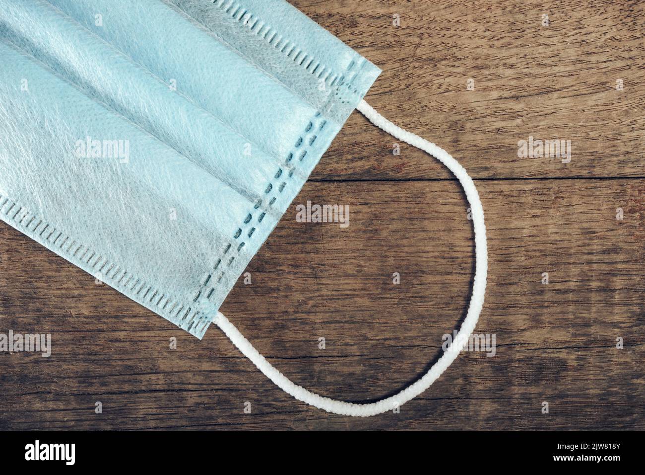Blue medical mask lies on a old brown wooden table background texture ...