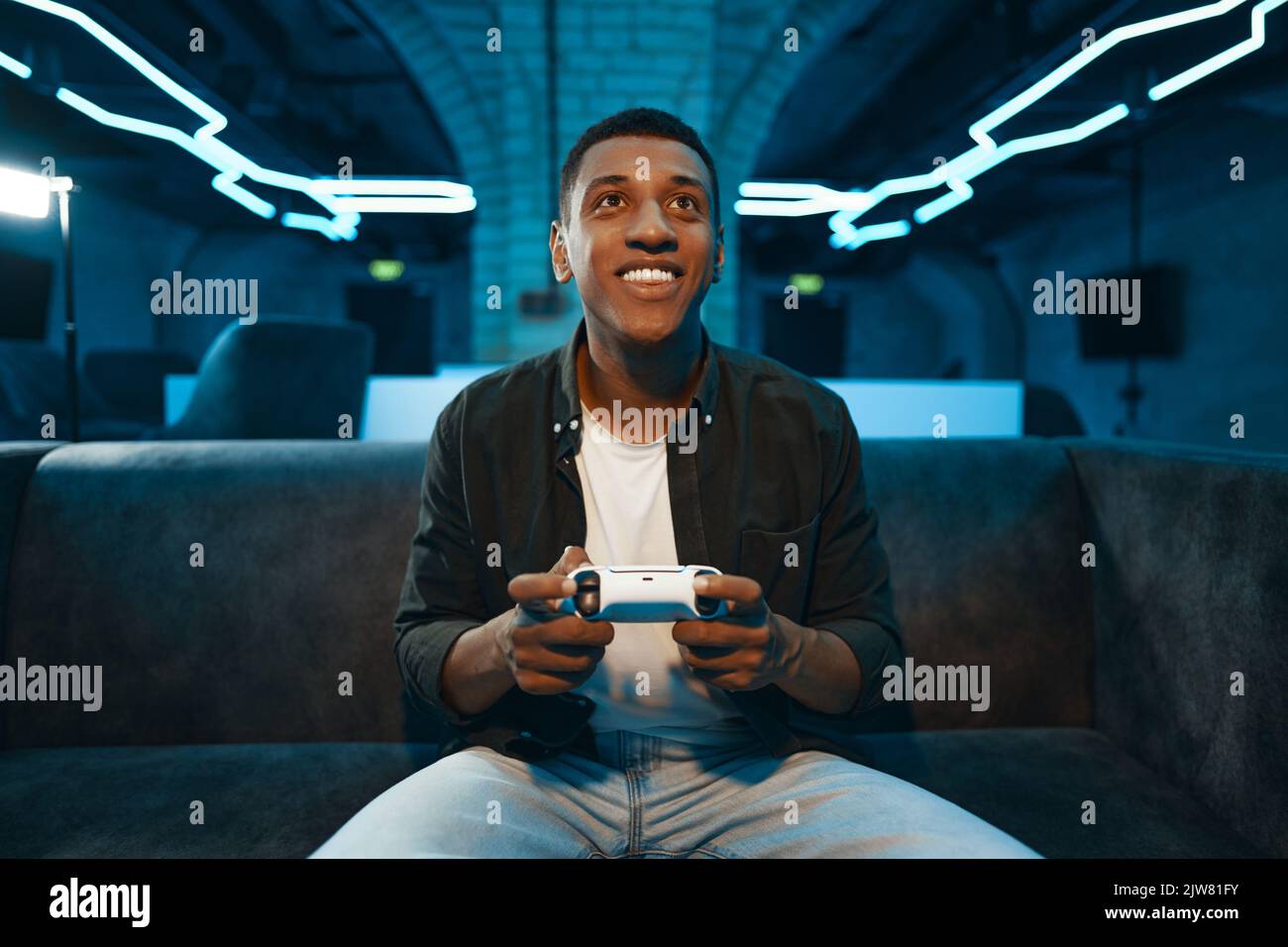 The player plays the console. Neon gaming room Stock Photo - Alamy