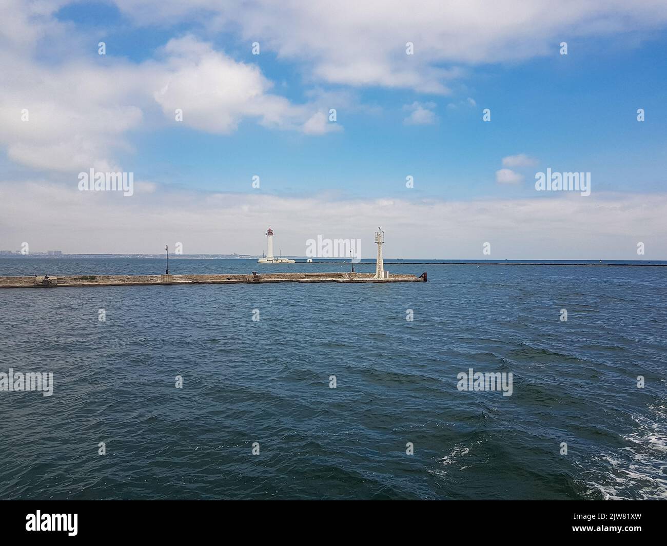 Seascape Sea with lighthouse, calm water and white clouds background ...
