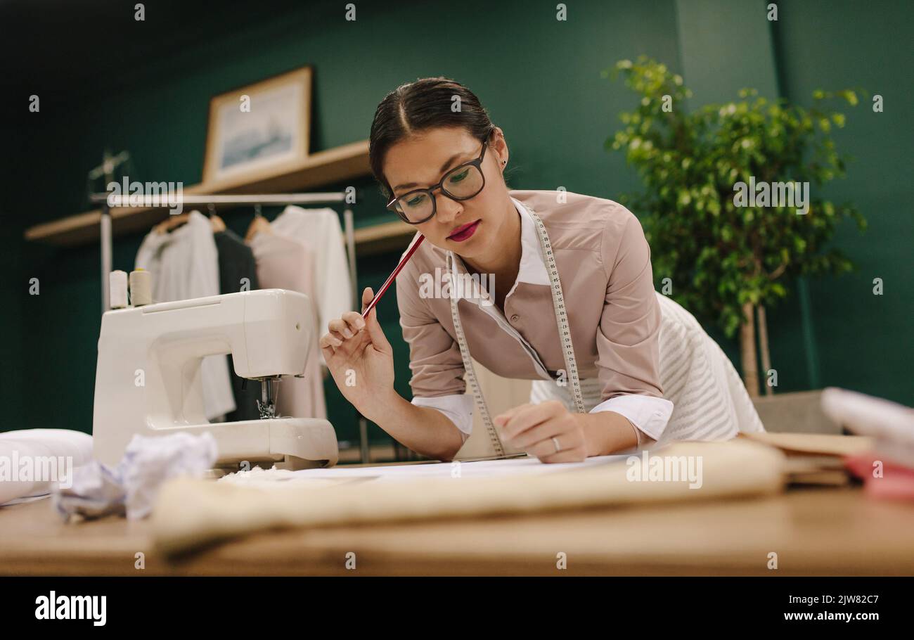 Young female fashion designer working on her dress designs in the ...