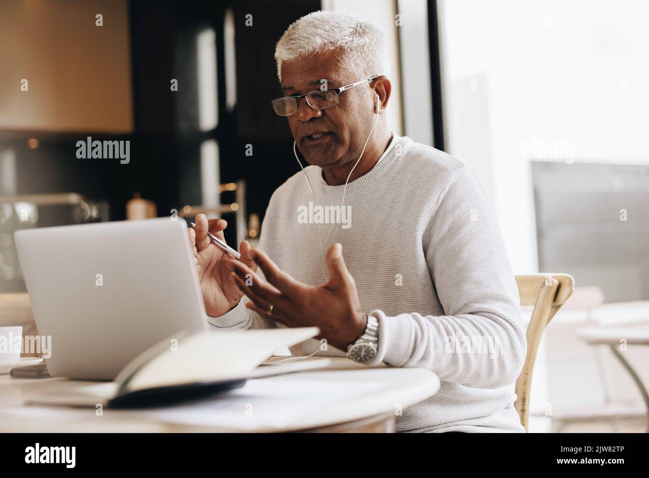 Senior businessman speaking during an online meeting in his home office ...