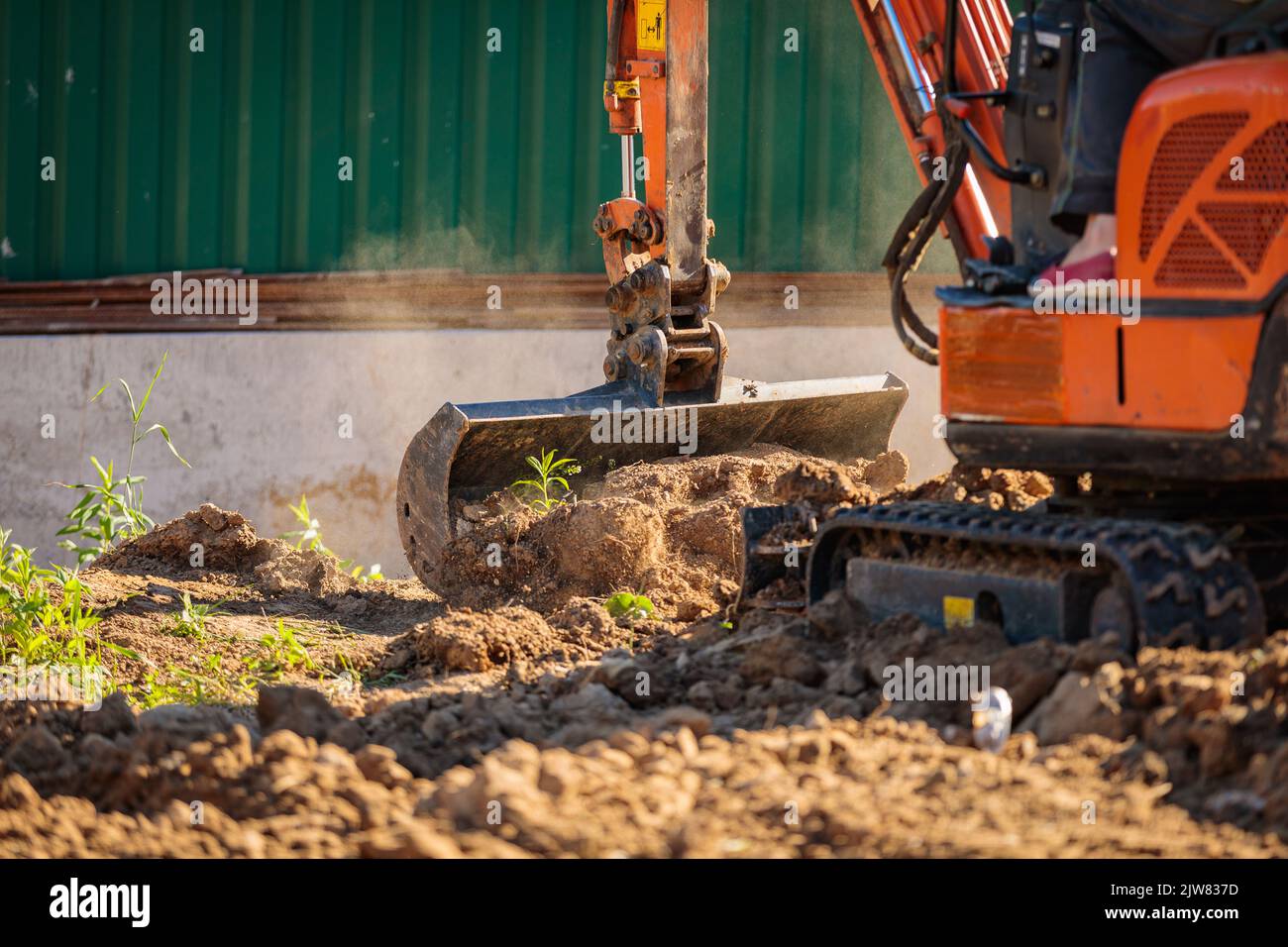 A minitractor rakes the earth with a bucket. Land works Stock Photo - Alamy
