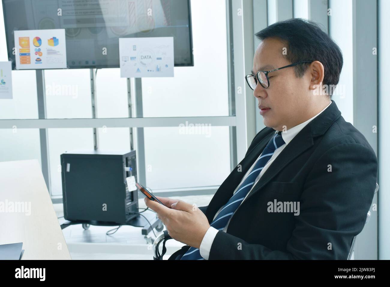 happy Asian business man using mobile phone in office room Stock Photo ...