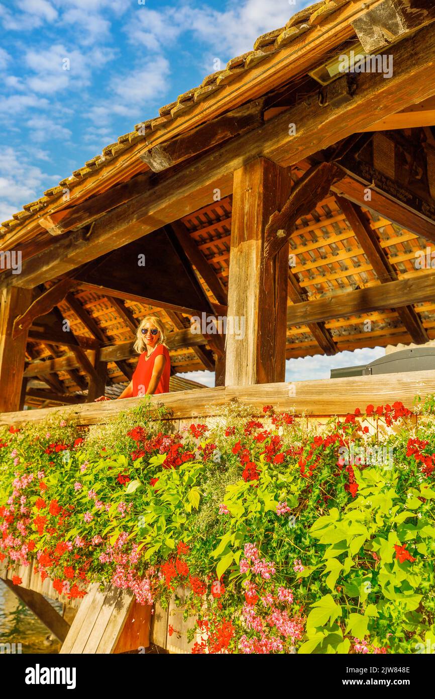 Blonde woman in red on the flowery bridge of Lucerne city, Reuss river ...