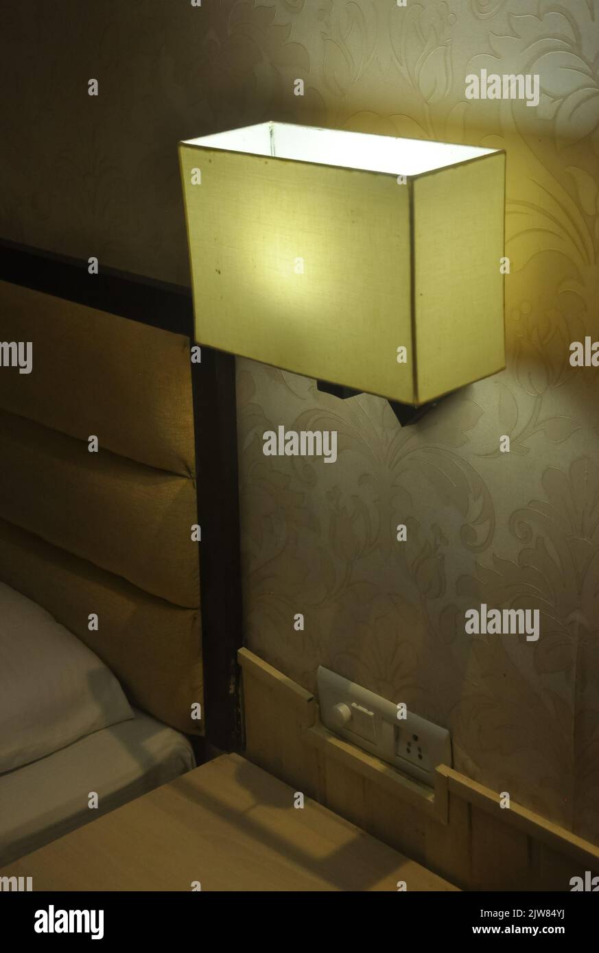 Side view of wall light lamp near to bed Stock Photo - Alamy