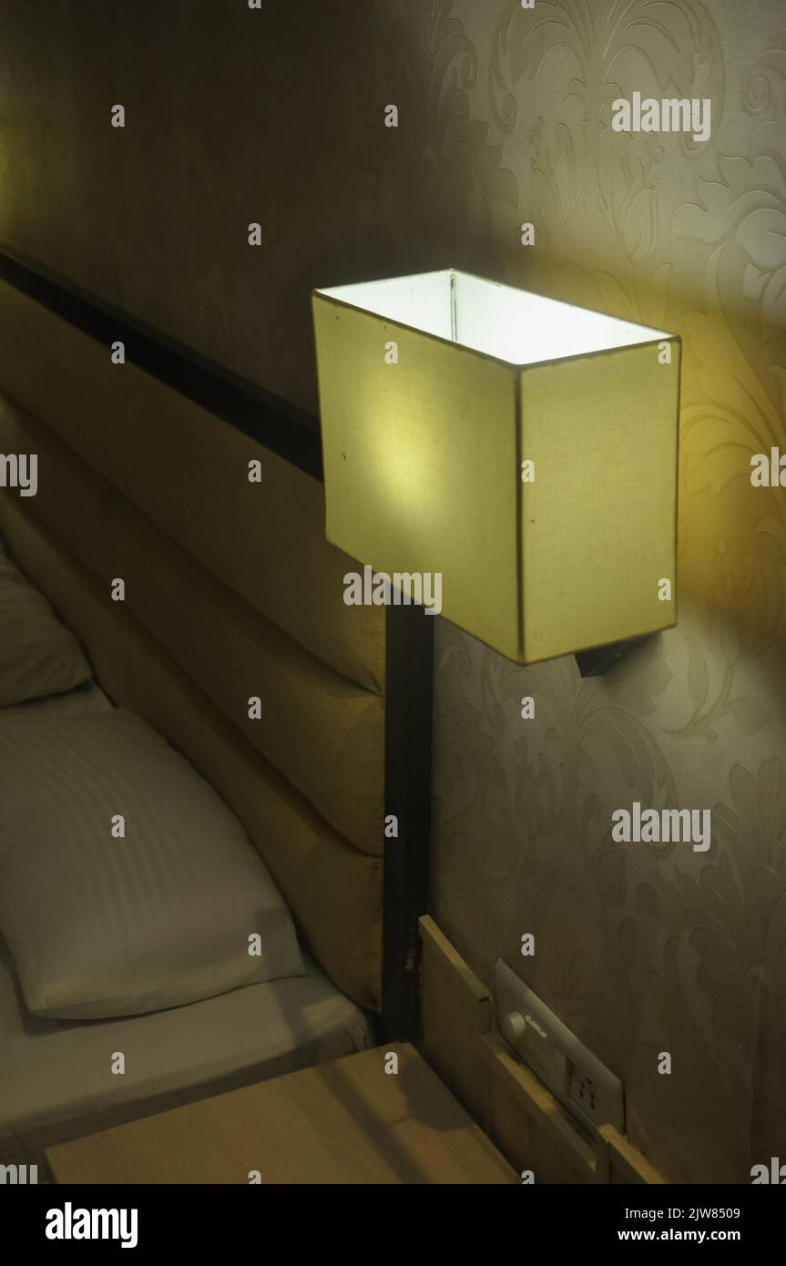 Side view of wall light lamp near to bed Stock Photo - Alamy