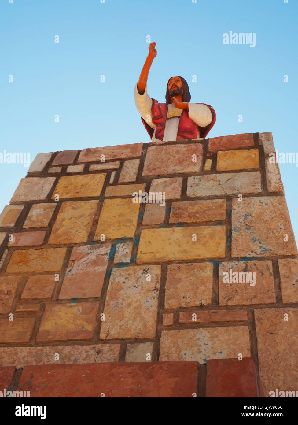 A vertical shot of a Jesus Christ statue over the brick wall Stock ...