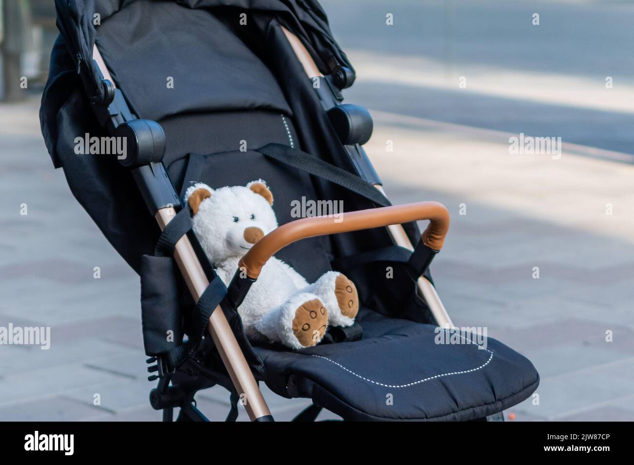 Soft toy teddy bear sitting in a baby stroller on blurred background of ...