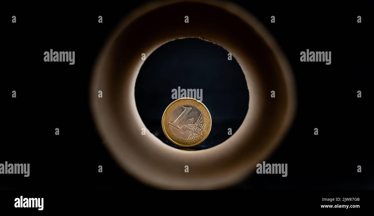 1 euro coin close-up on black background inside blurred paper tube ...