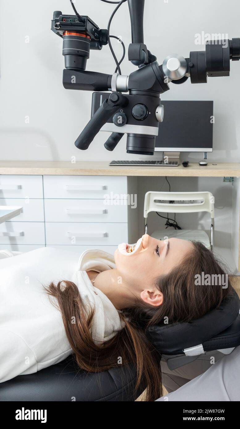 Using dental microscope treating patient teeth at dental clinic office ...