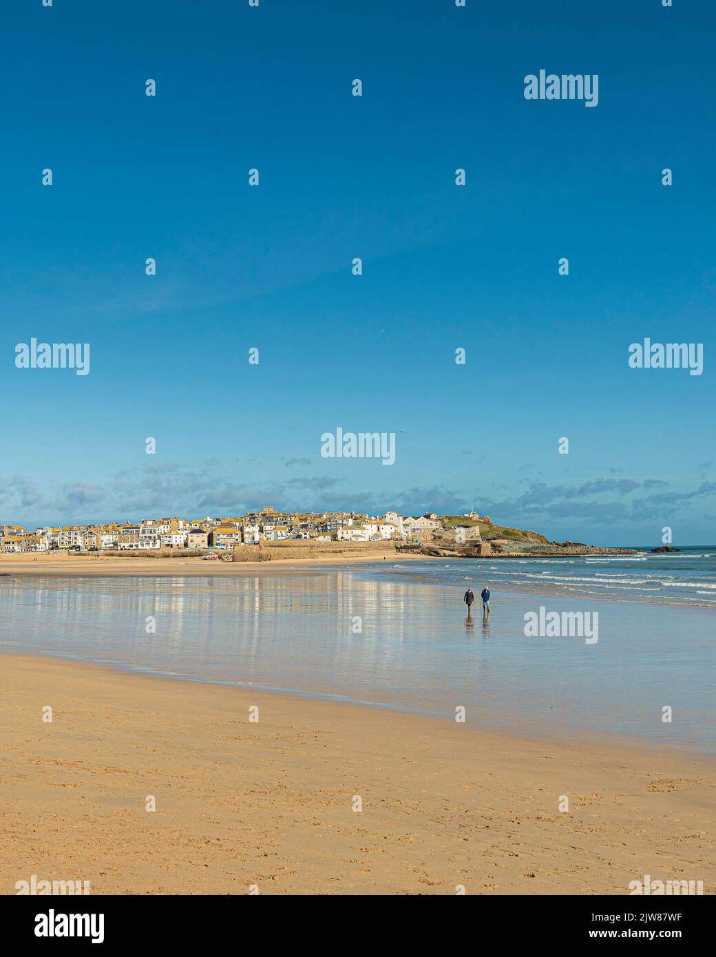 Couple taking a long walk at low tide on Porthminster beach towards St ...