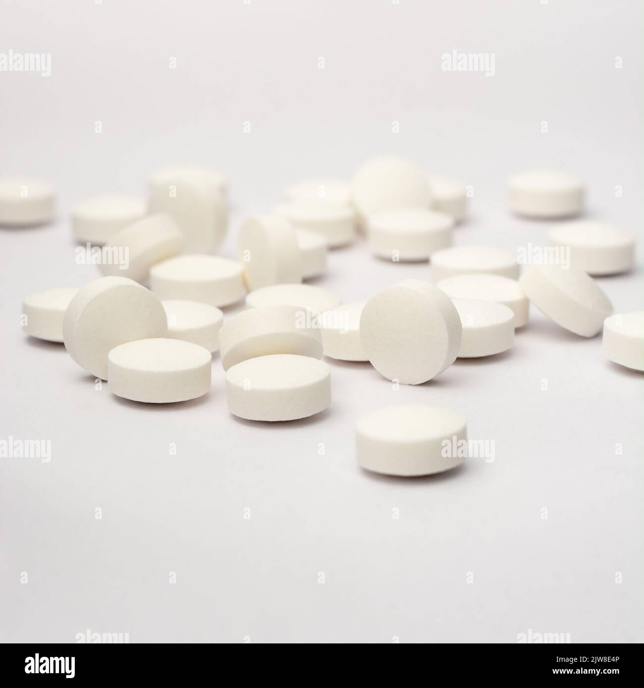 white round pills or tablets scattered on white background, medical ...