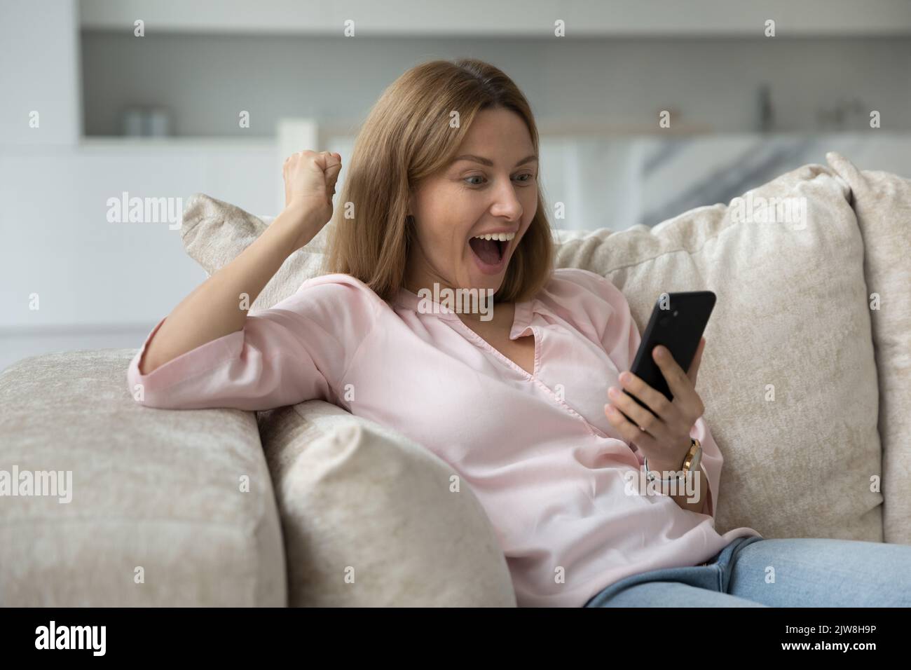 Cheerful excited mobile phone user woman staring at screen Stock Photo ...