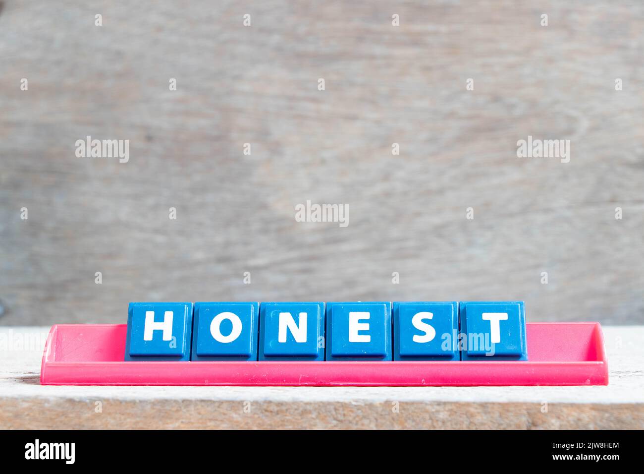 Tile alphabet letter with word honest in red color rack on wood ...