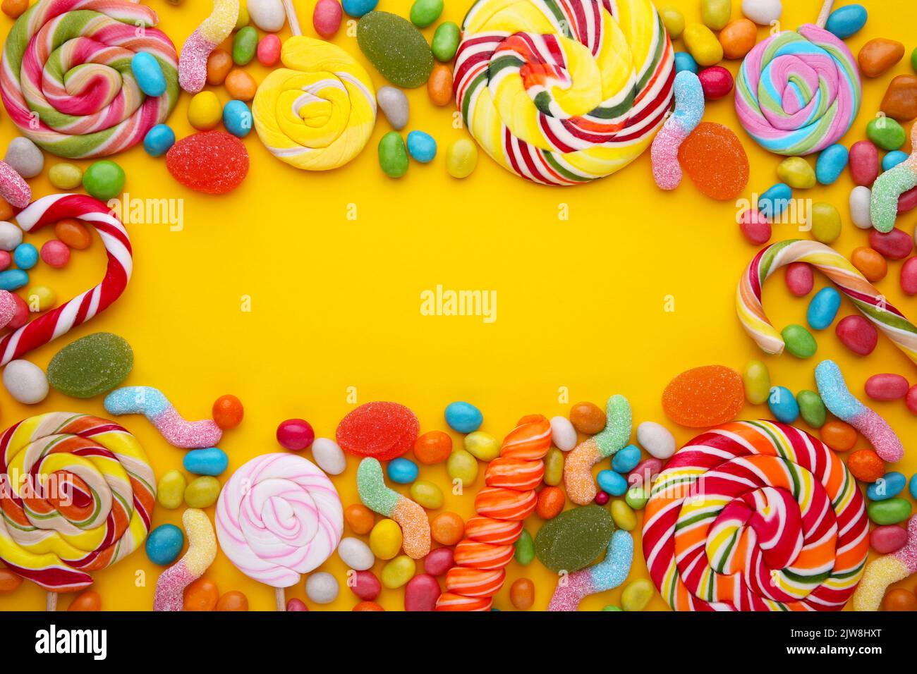 Colorful lollipops and different colored round candy on yellow Stock ...