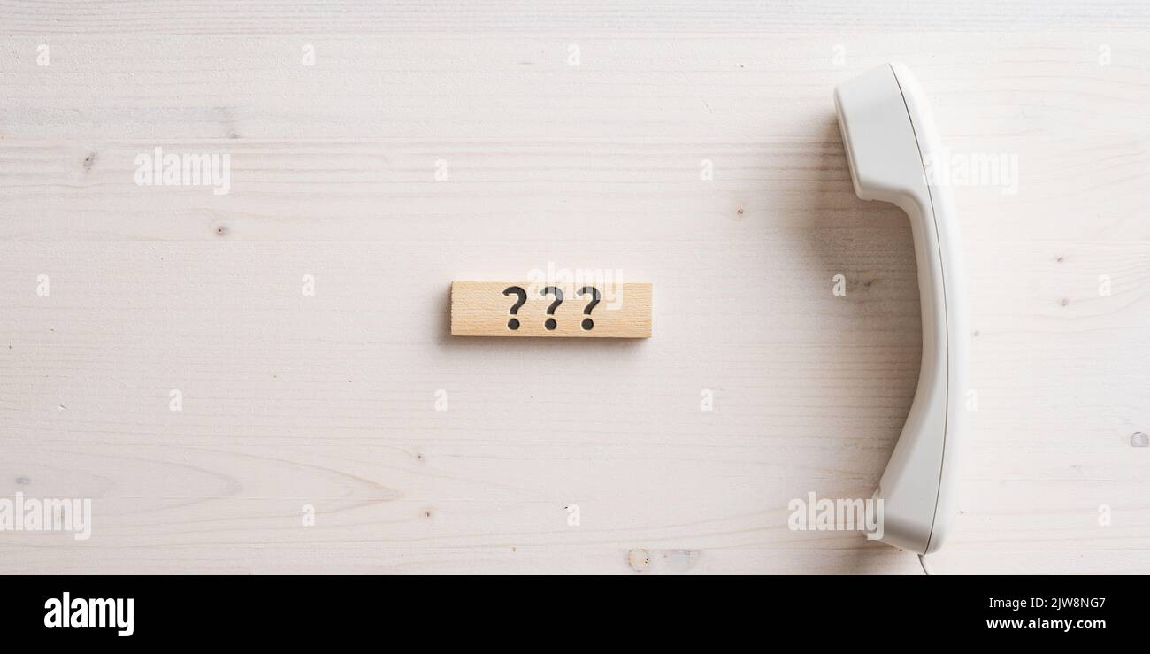 Three question marks written on wooden peg placed next to a white ...