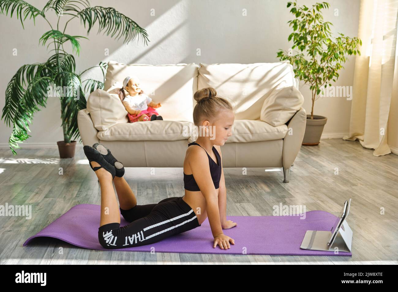 Kid repeating exercises while watching online yoga gymnastics session ...
