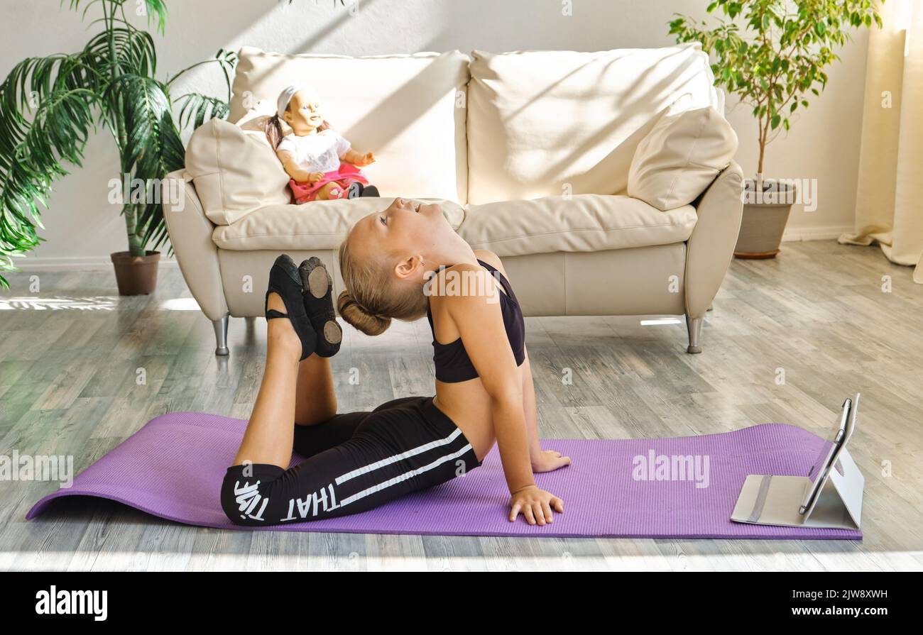 Kid repeating exercises while watching online yoga gymnastics session ...