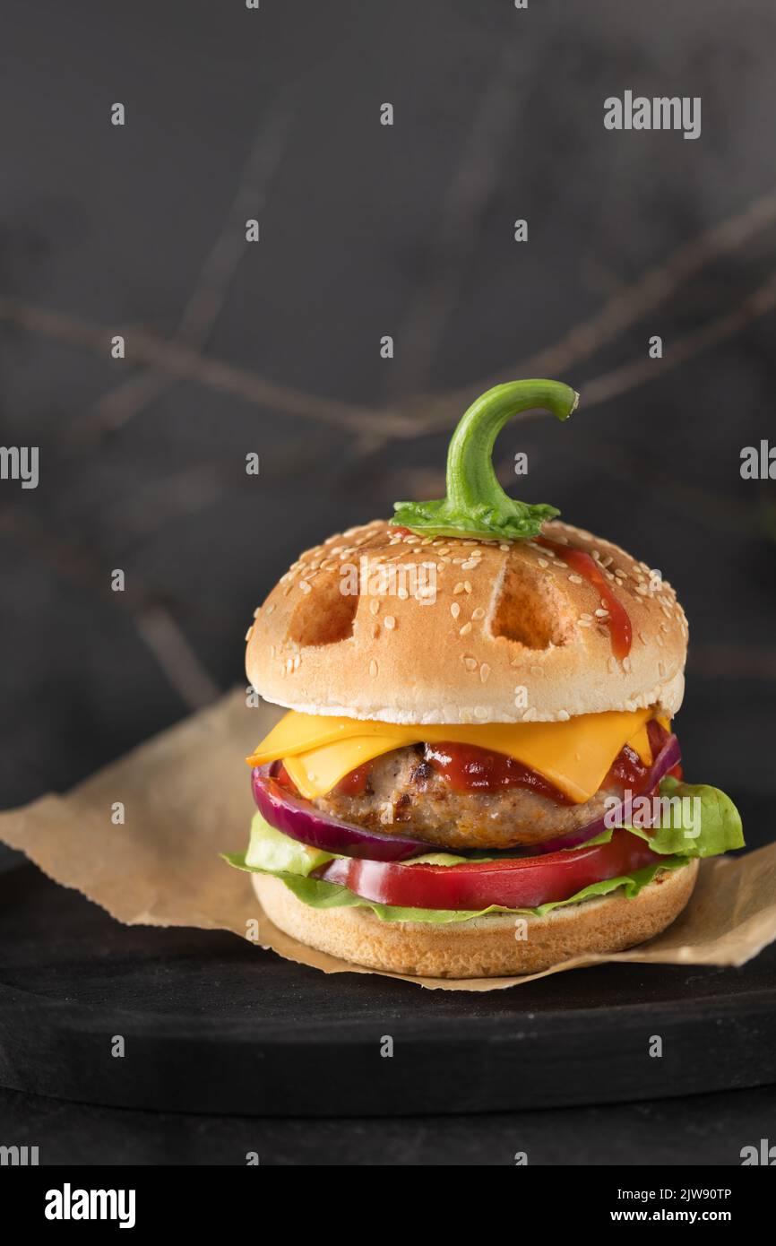 Halloween burger in a shape of pumpkin head jack o lantern on black ...