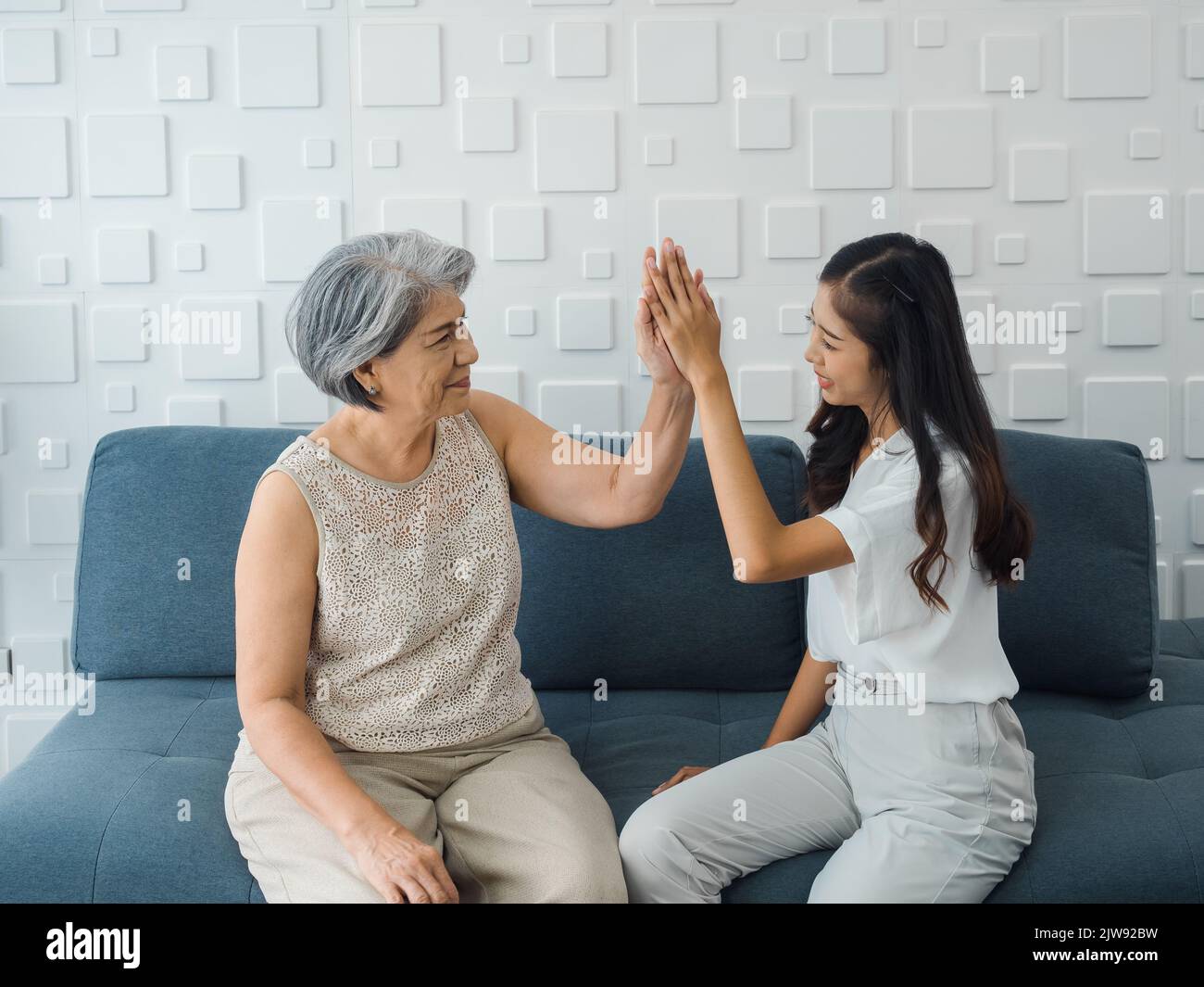 Asian elderly woman, mom giving high five to her cheerful daughter ...