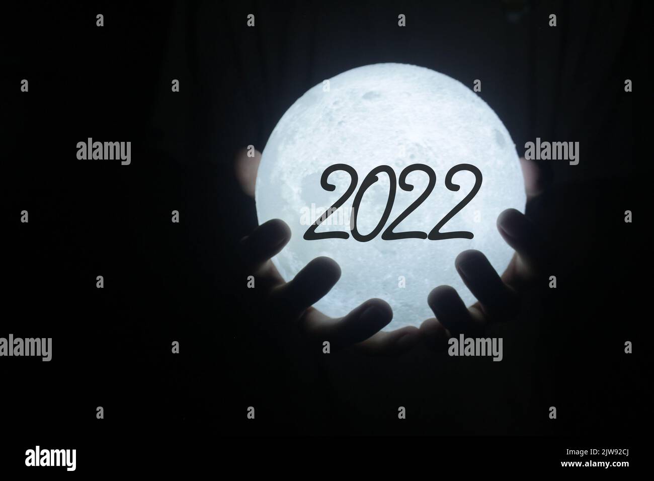2022 light in hand on black background. Person holding 2022 light in ...