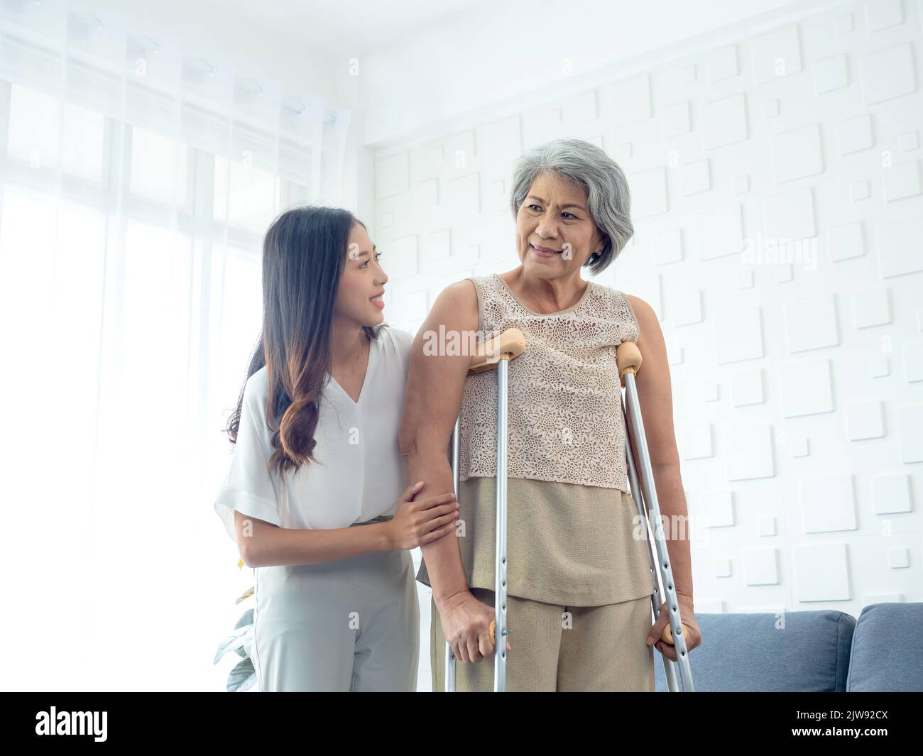 Elderly woman trying to walk on crutches standing held and supported in ...