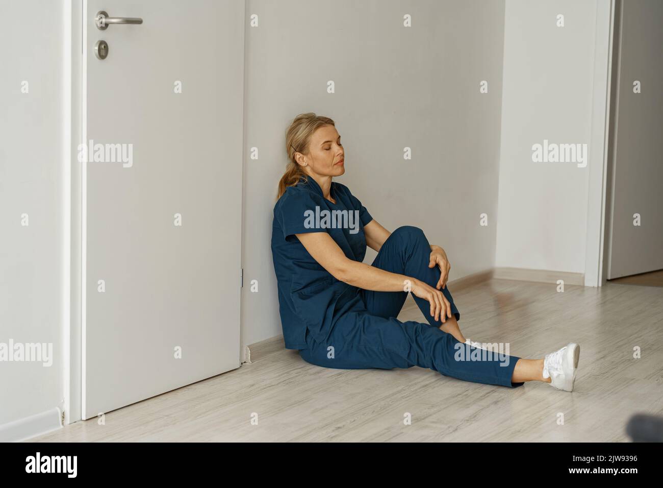Tired nurse sits on floor in the lobby of medicine clinic after a hard ...