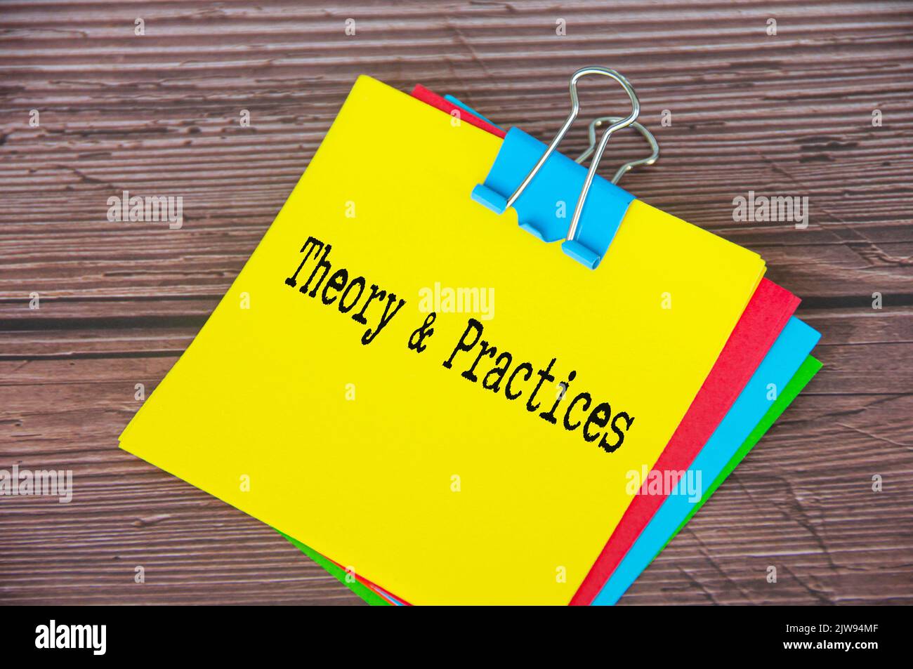 Theory and practices text on yellow notepad with wooden desk background ...