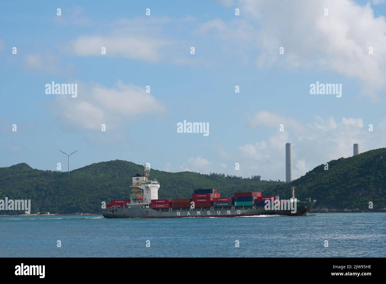A cargo ship riding on Waterfall Bay waters on the background of a hill ...